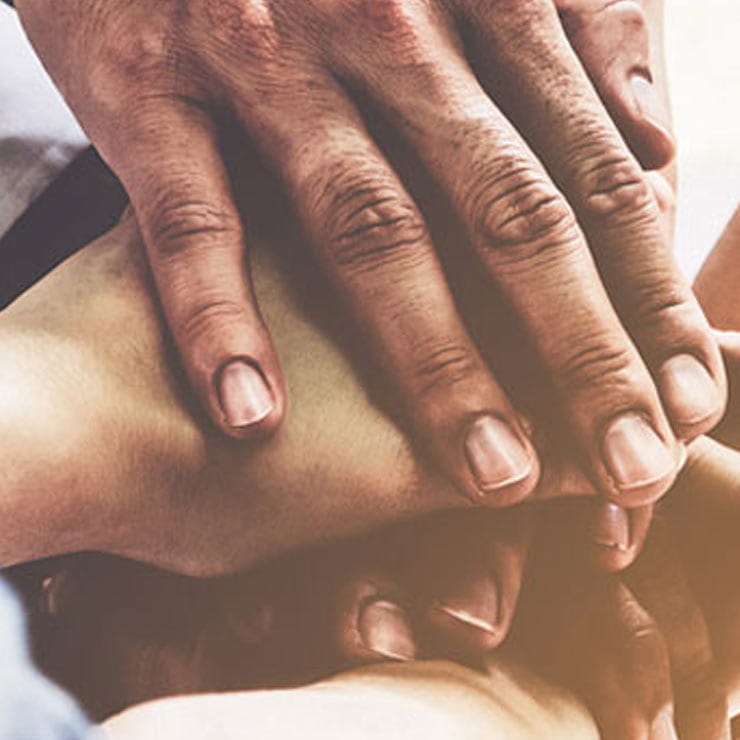 A group of hands overlap at a volunteering event