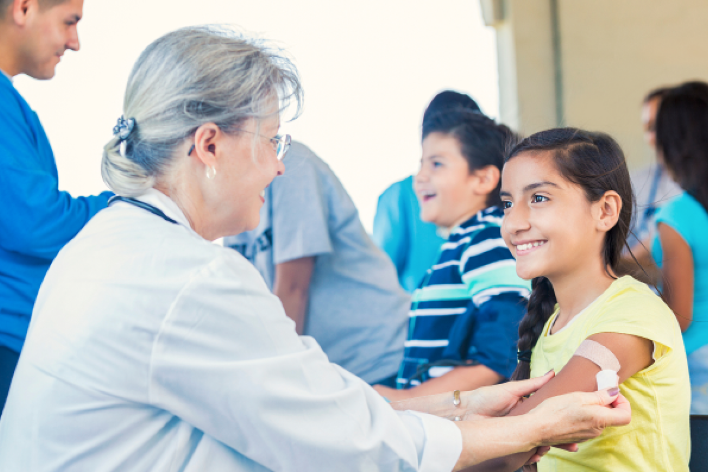 A young girl smiles while receiving treatment from a female doctor
