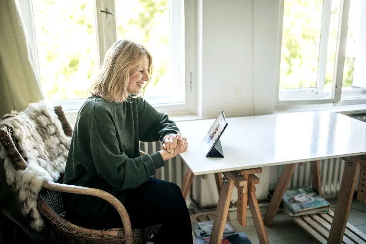 A smiling mature woman on her tablet at home during a video call