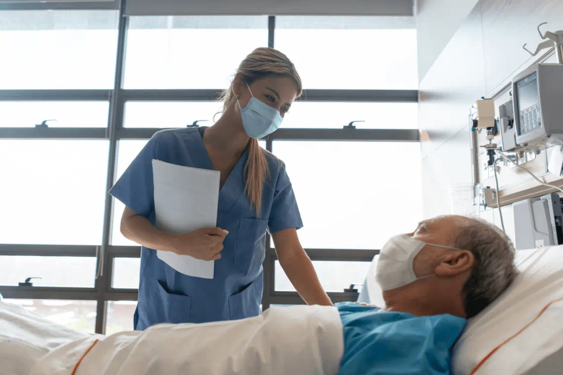 Woman attending to a patient in a hospital bed
